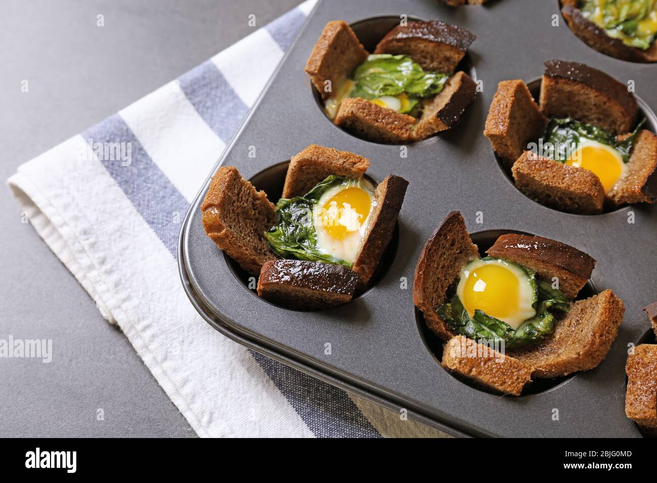 Baking mold with eggs and spinach on gray table Stock Photo - Alamy