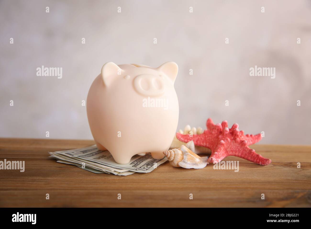 Cute piggy bank with money, shell and starfish on wooden table Stock ...