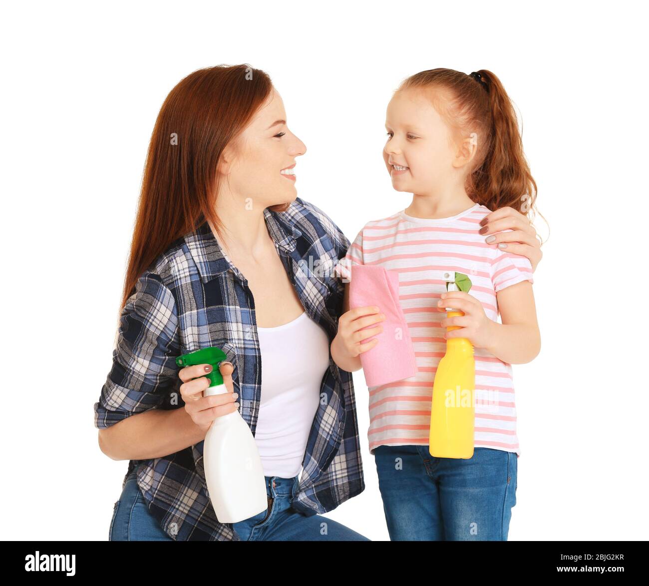 Little girl and her mother with cleaning supplies on white background ...