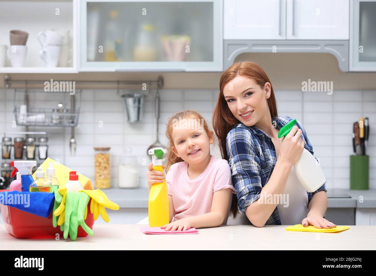 Little girl and her mother cleaning counter in kitchen at home Stock ...