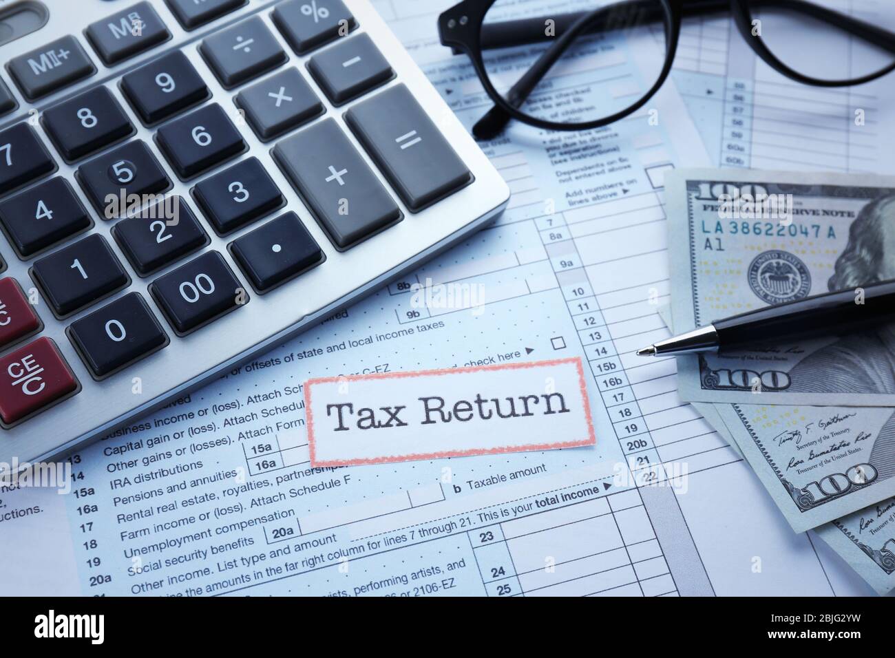 Paper sheet with text TAX RETURN, calculator, pen, spectacles and ...