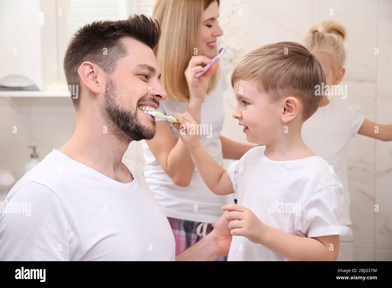 Cute little boy helping his father to brush teeth in bathroom Stock ...