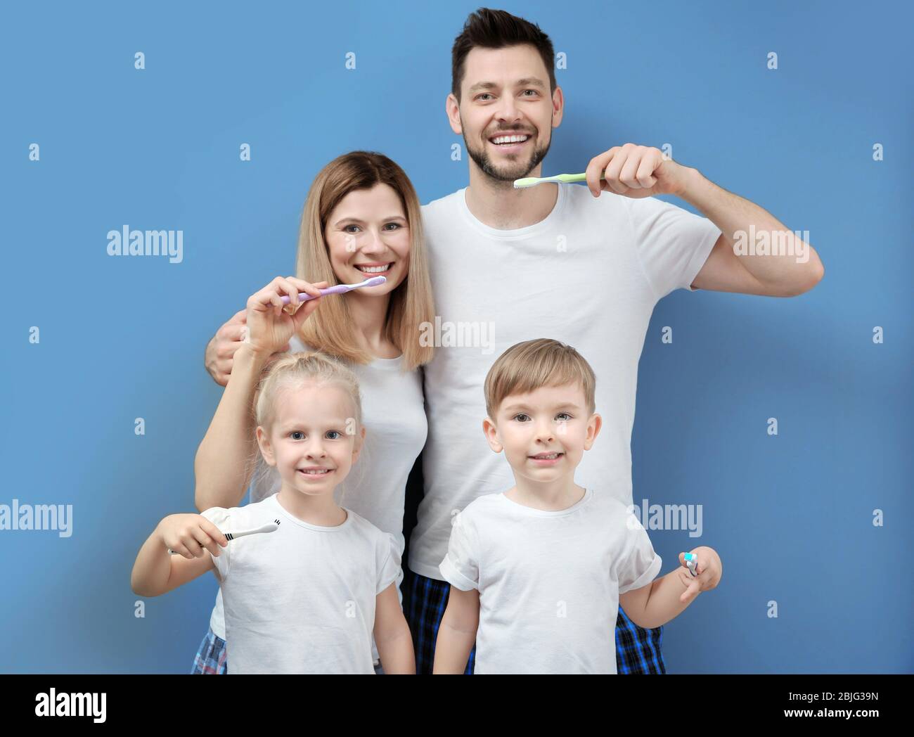 Young family brushing teeth on blue background Stock Photo - Alamy