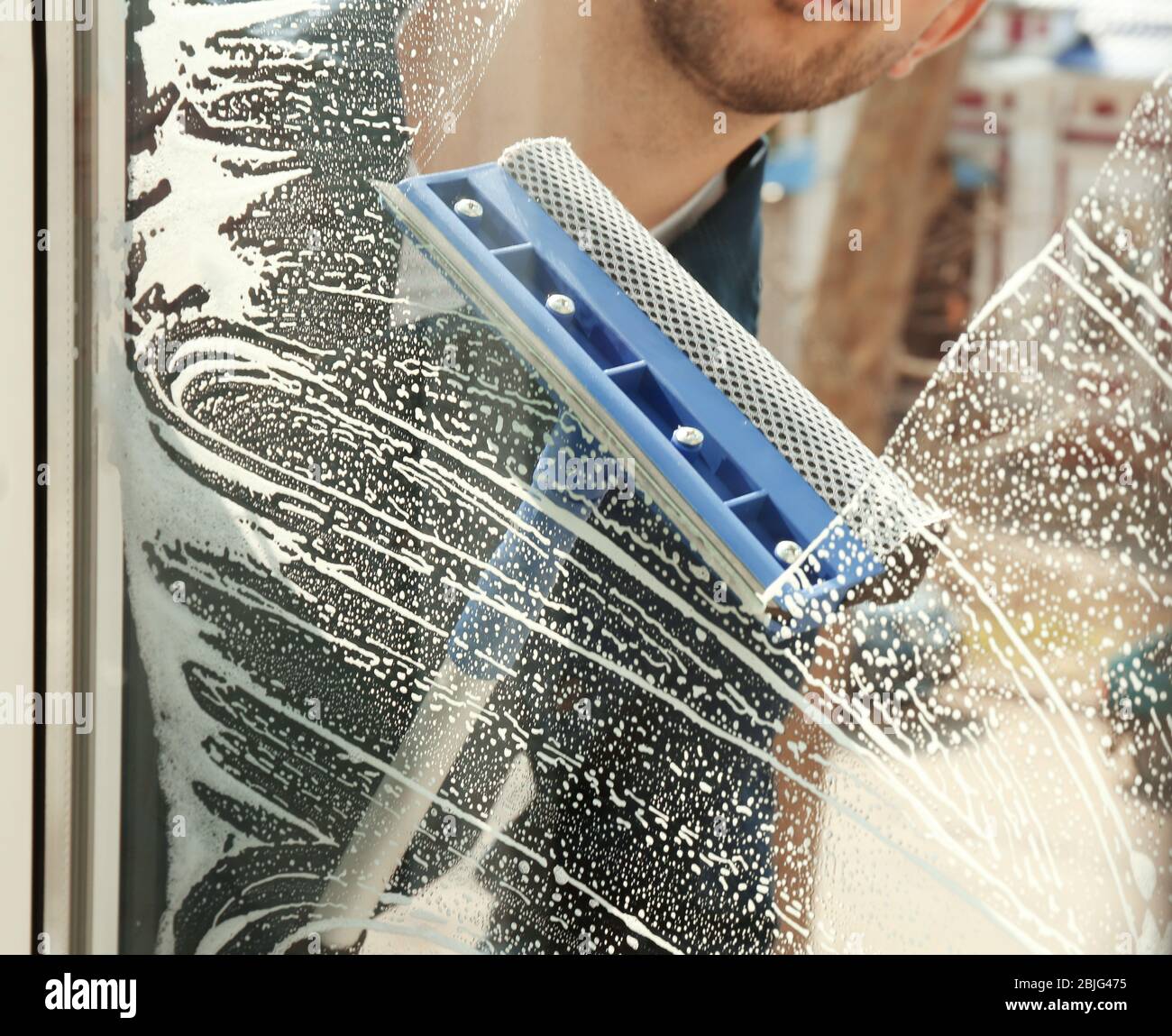 Young man washing window, view through glass Stock Photo - Alamy