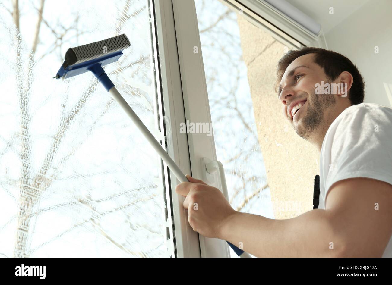 Young man washing window in office Stock Photo - Alamy