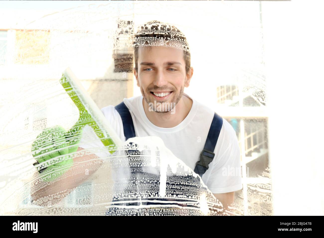 Young man washing window, view through glass Stock Photo - Alamy