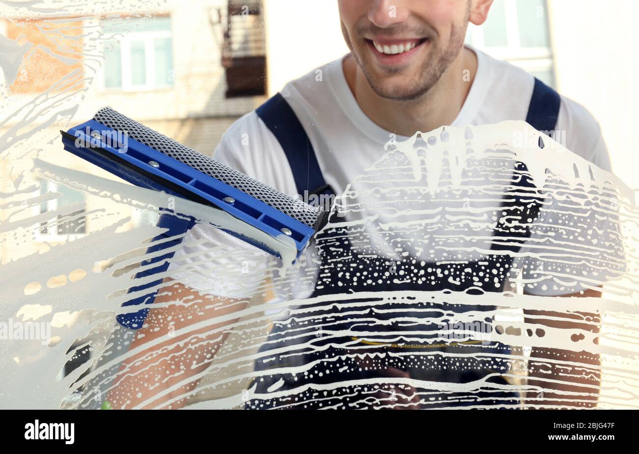 Young man washing window, view through glass Stock Photo - Alamy