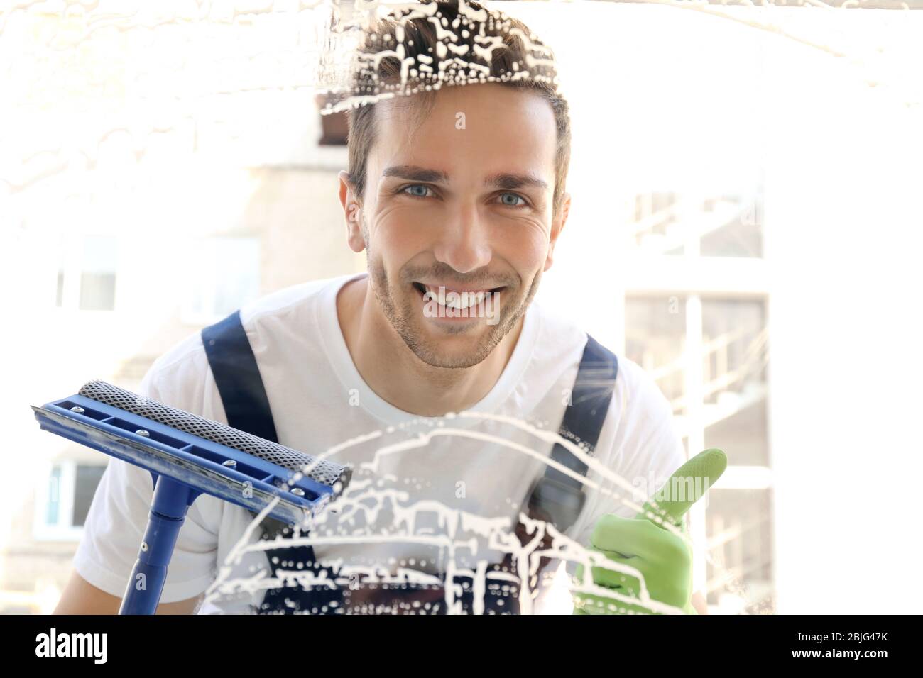 Young man washing window, view through glass Stock Photo - Alamy