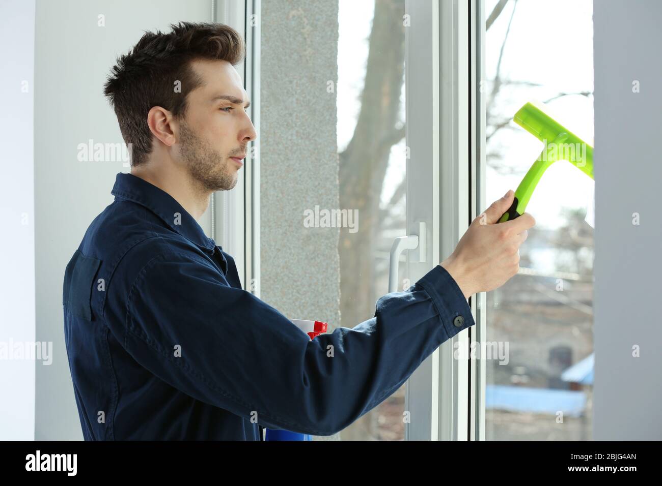 Young man washing window in office Stock Photo - Alamy