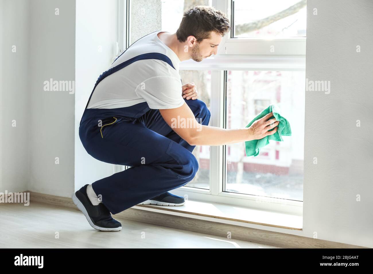 Young man cleaning window in office Stock Photo - Alamy