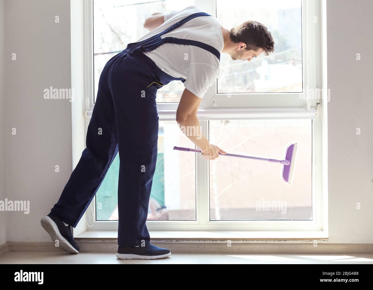 Young man washing window in office Stock Photo - Alamy