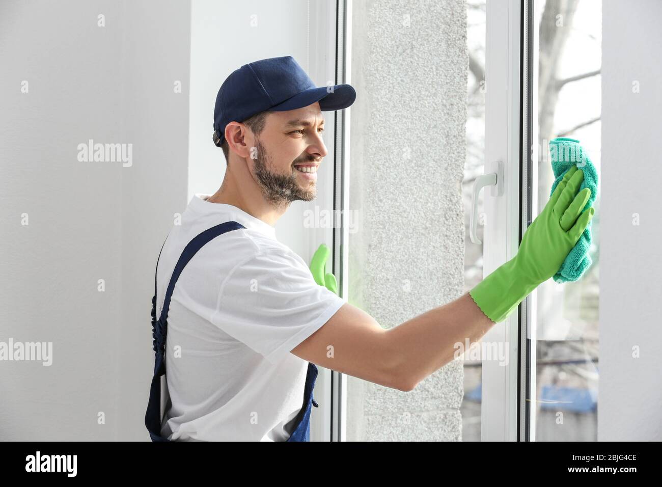 Young man cleaning window in office Stock Photo - Alamy