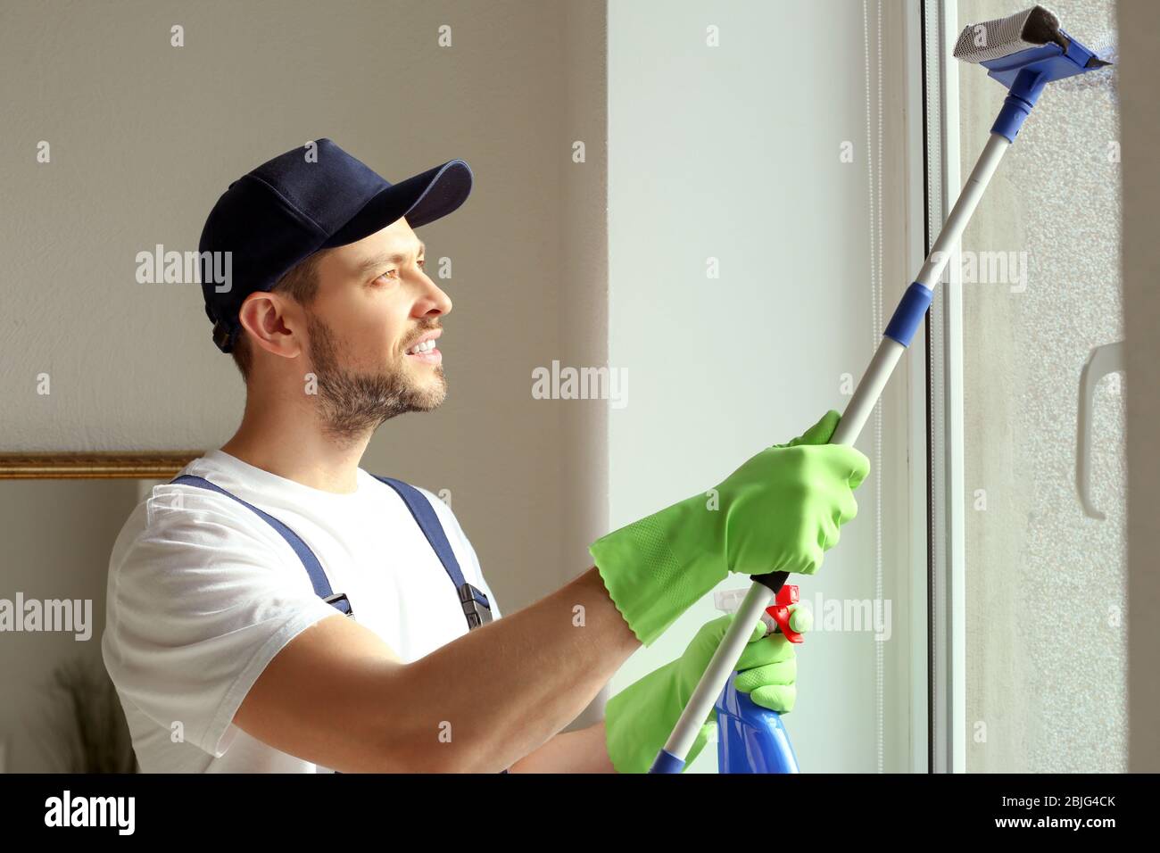 Young man washing window in office Stock Photo - Alamy