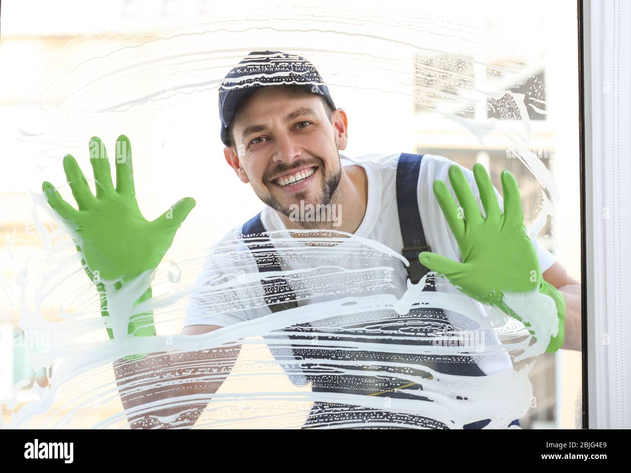 Young man washing window in office, view through glass Stock Photo - Alamy
