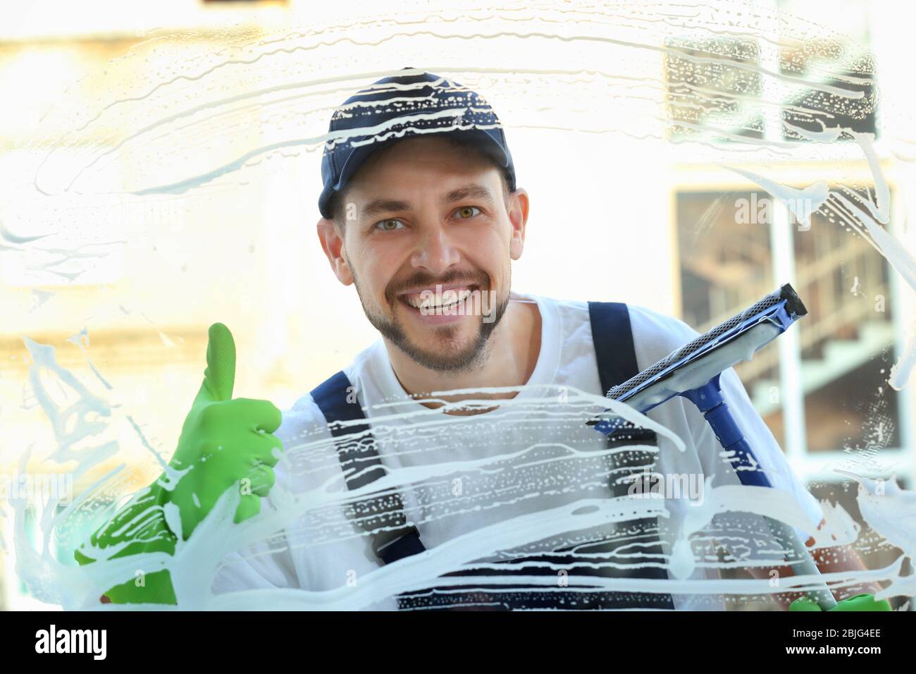 Young man washing window in office, view through glass Stock Photo - Alamy