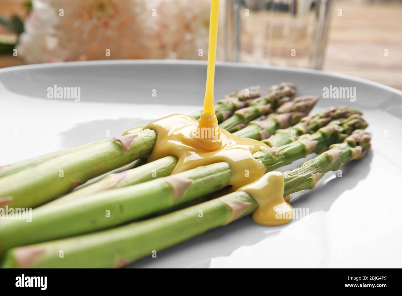 Pouring cheese sauce onto asparagus, close up Stock Photo - Alamy