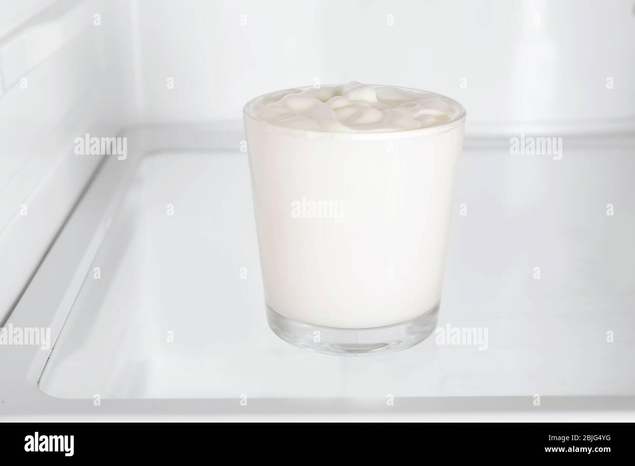 Glass with yogurt standing in fridge Stock Photo - Alamy