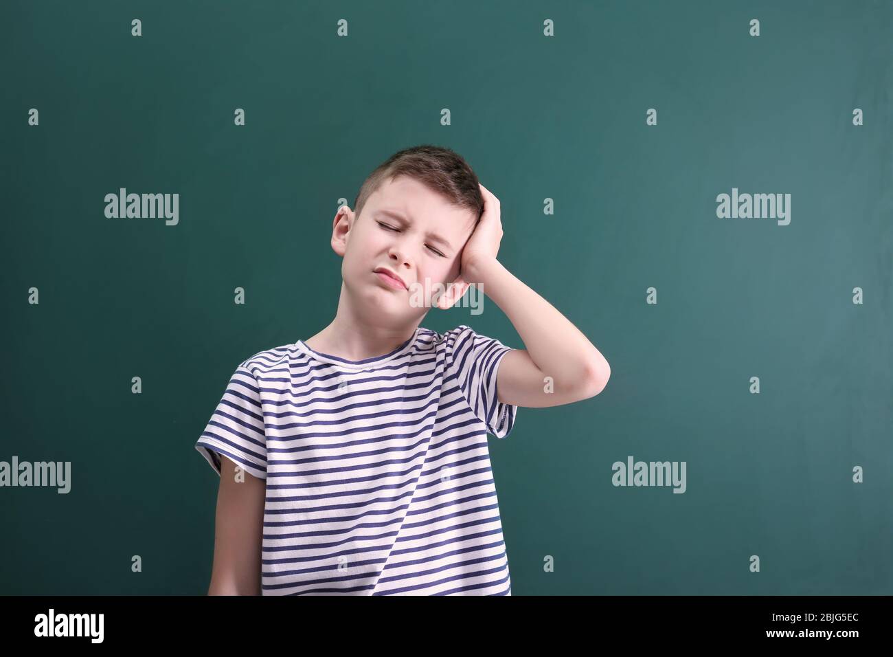 Cute boy suffering from headache on color background Stock Photo - Alamy