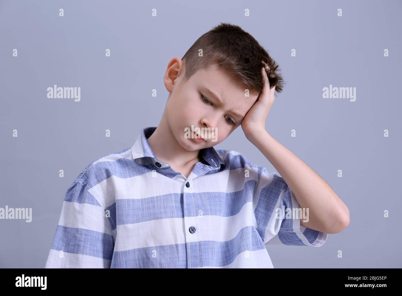 Cute boy suffering from headache on color background Stock Photo - Alamy