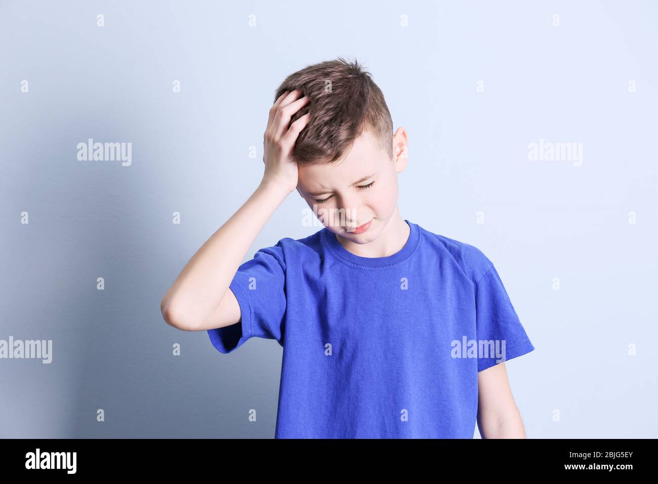 Cute boy suffering from headache on color background Stock Photo - Alamy