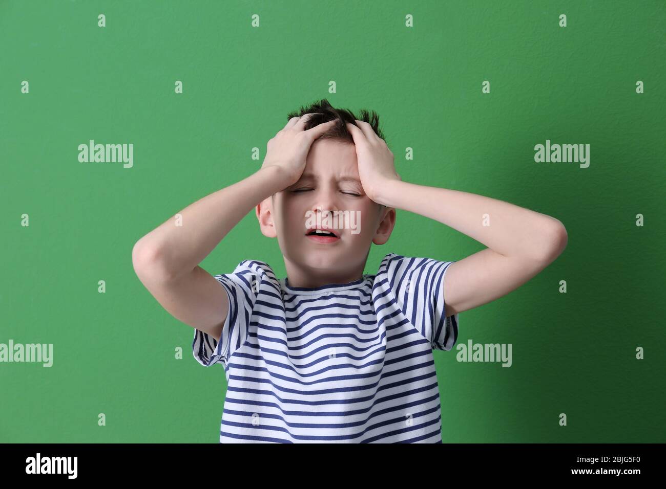 Cute boy suffering from headache on color background Stock Photo - Alamy
