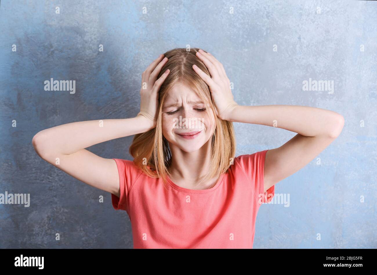 Cute girl suffering from headache on color background Stock Photo - Alamy