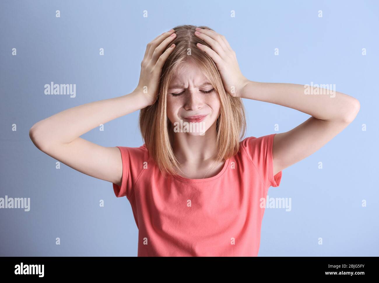 Cute girl suffering from headache on color background Stock Photo - Alamy