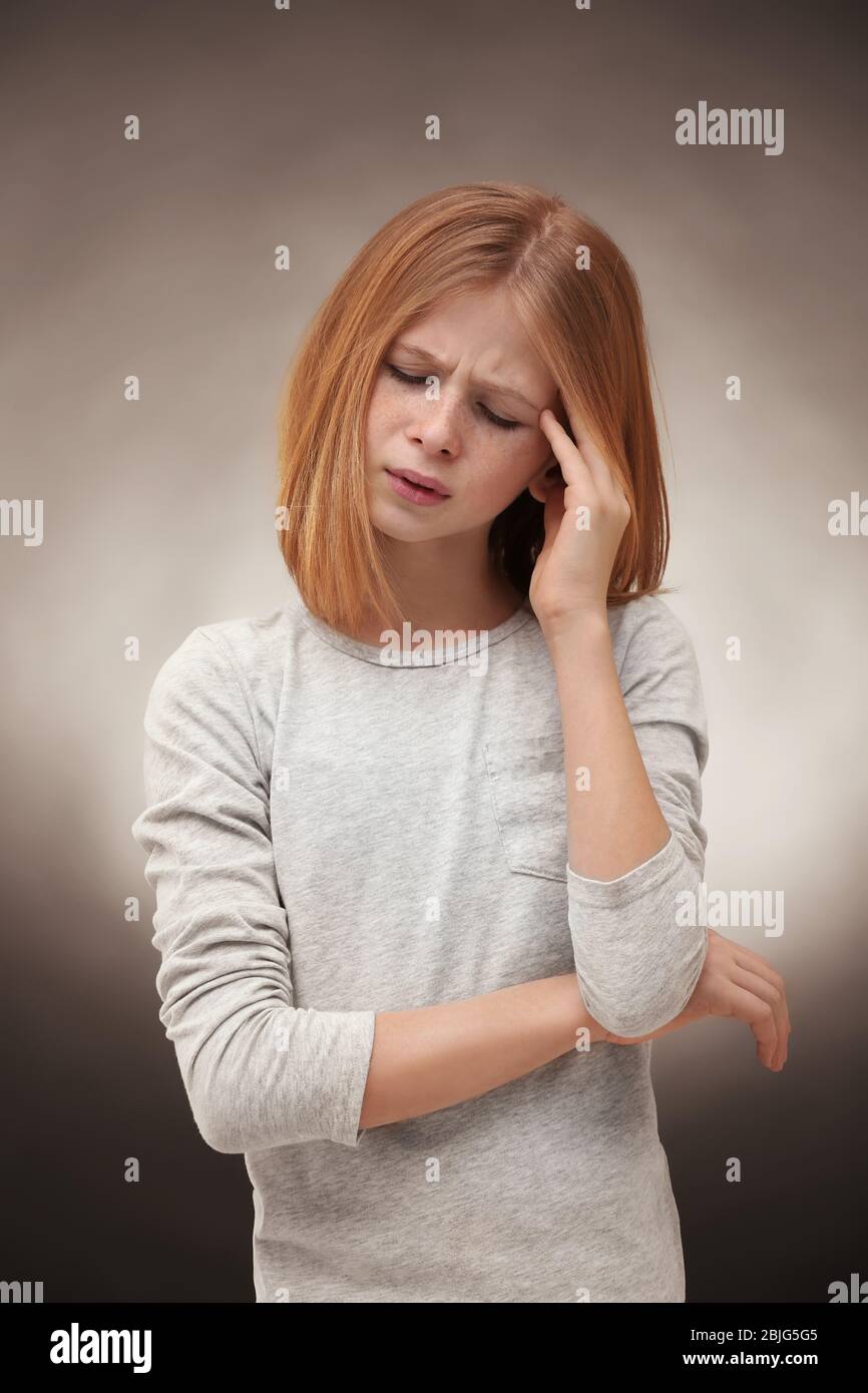 Cute girl suffering from headache on grey background Stock Photo - Alamy