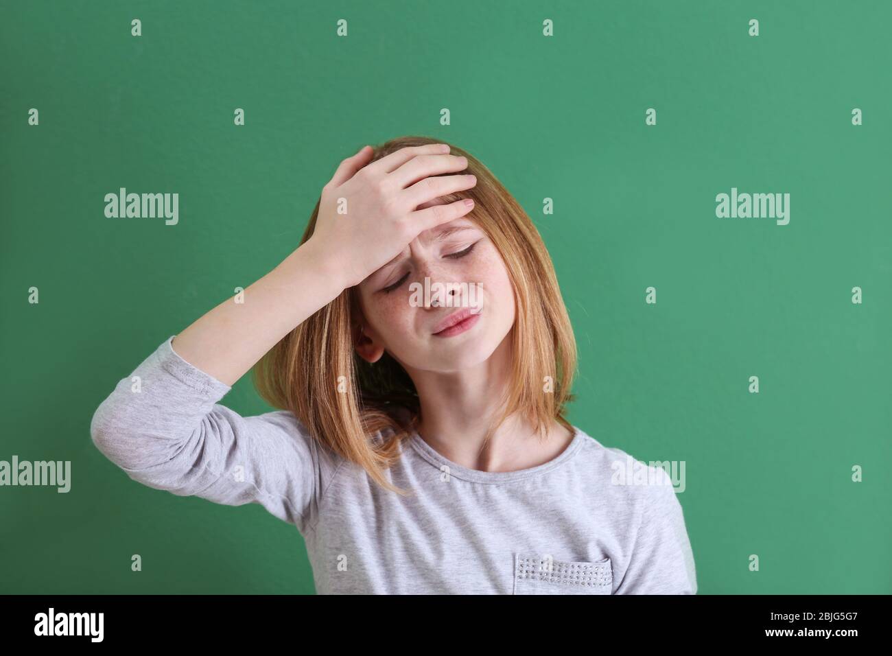 Cute girl suffering from headache on color background Stock Photo - Alamy