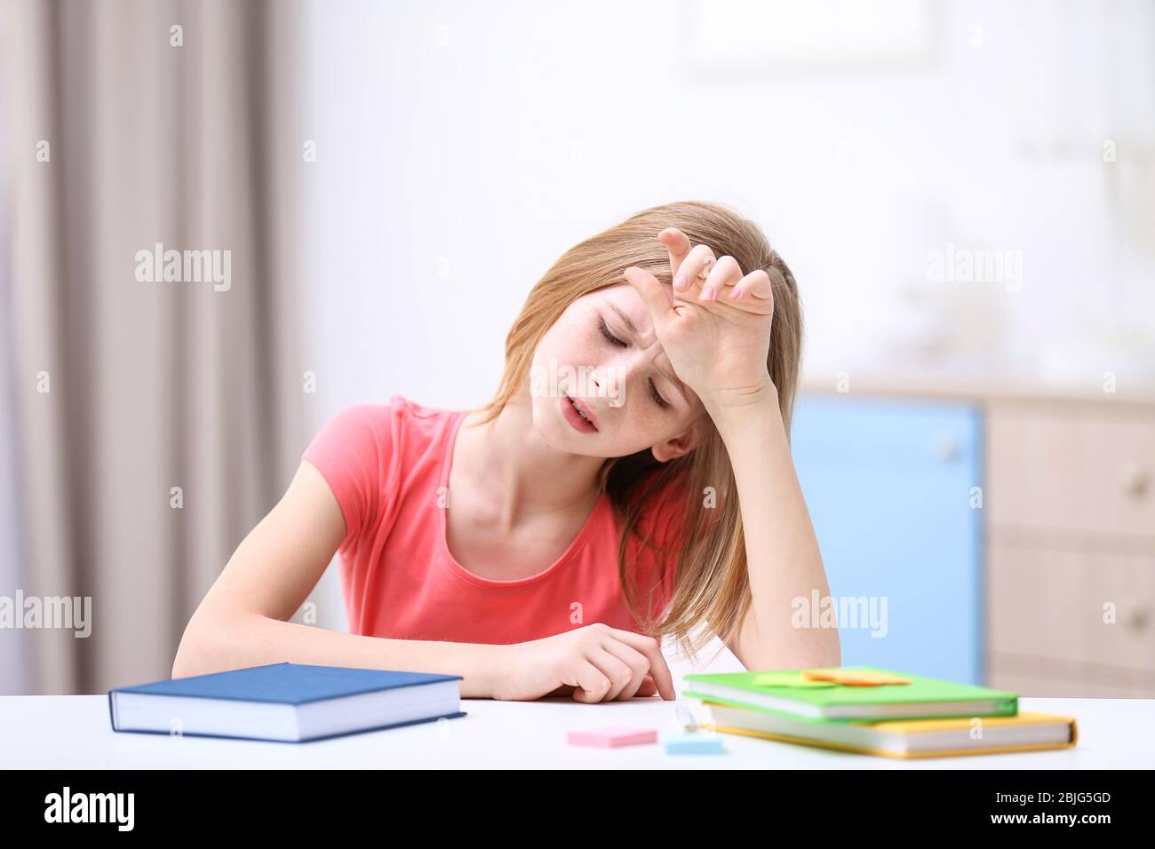 Cute girl suffering from headache while doing lessons at home Stock ...