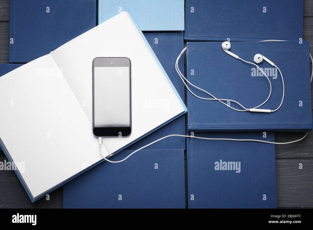 Audiobook concept. Many hardcover books and mobile phone with earphones ...