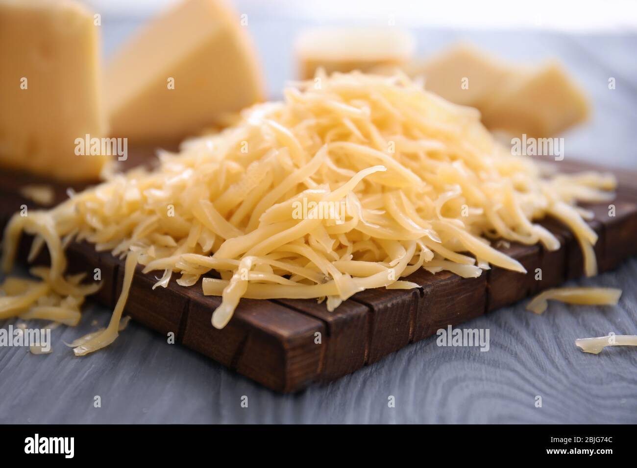 Wooden board with grated cheese on table Stock Photo - Alamy