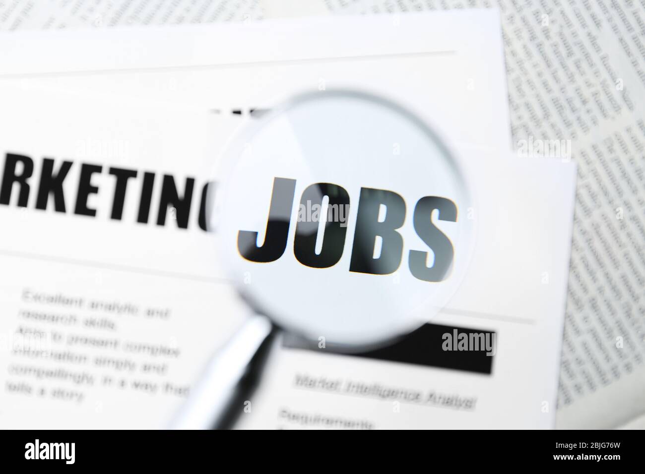 Paper sheet with word JOBS through magnifier, closeup. Marketing ...
