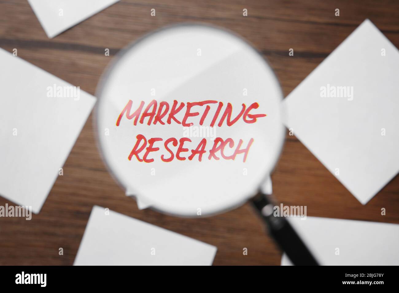 Paper note with text MARKETING RESEARCH through magnifier, closeup ...