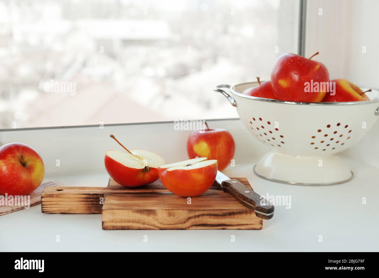 Wooden board with fresh apple cuts in half on windowsill Stock Photo ...