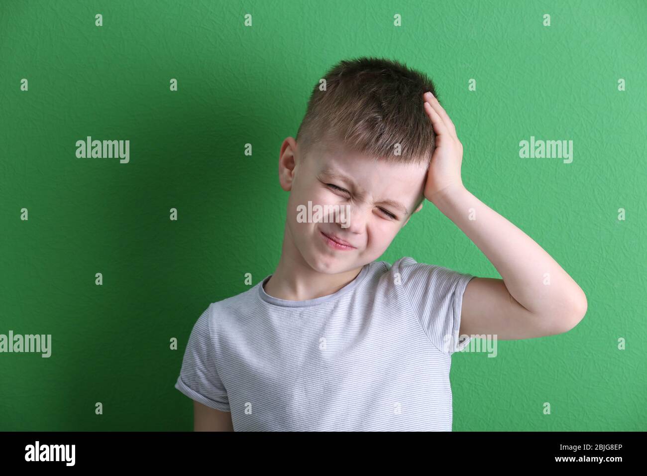 Little boy suffering from headache on color background Stock Photo - Alamy