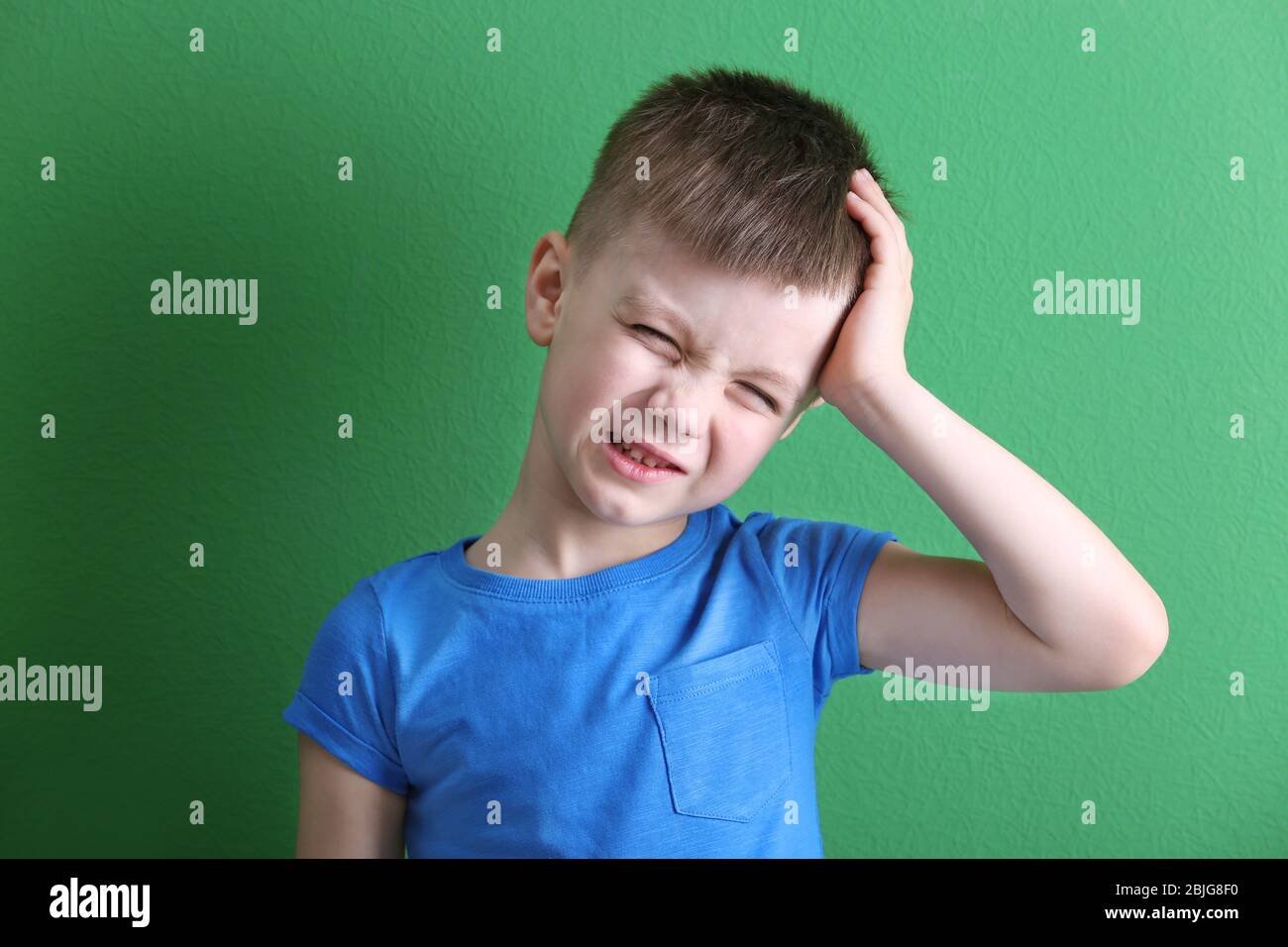 Little boy suffering from headache on color background Stock Photo - Alamy