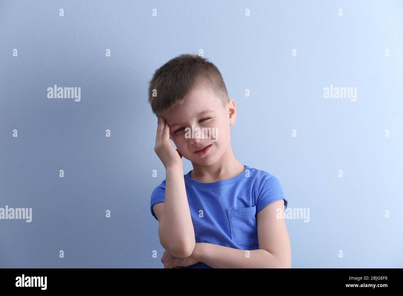 Little boy suffering from headache on color background Stock Photo - Alamy