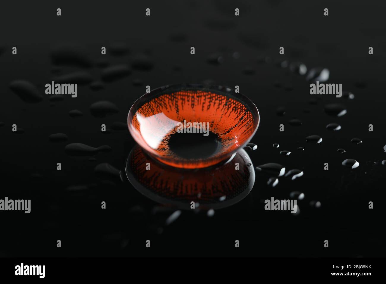 Red contact lens on wet black background Stock Photo - Alamy