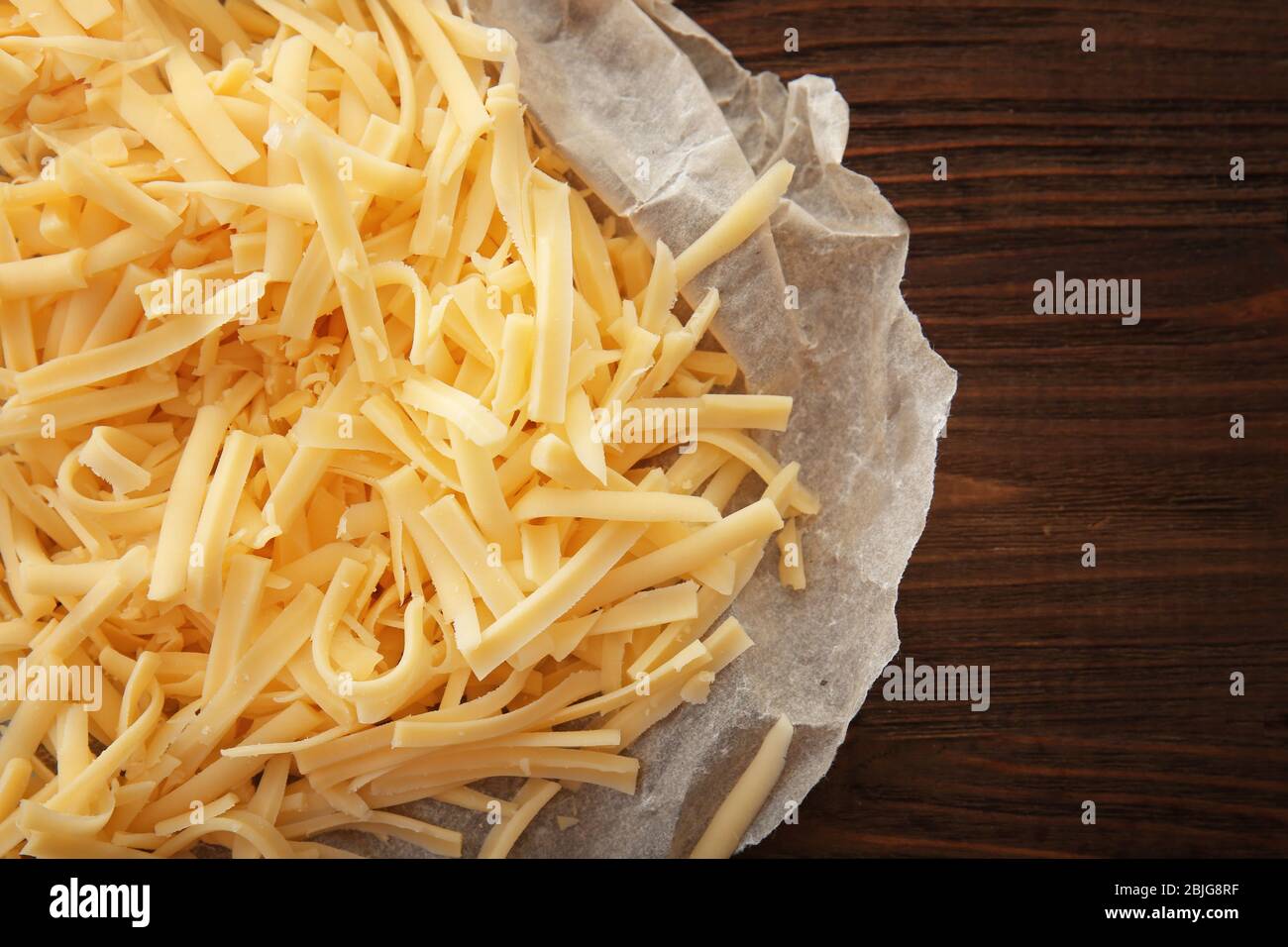 Grated cheese and food paper on wooden background Stock Photo - Alamy