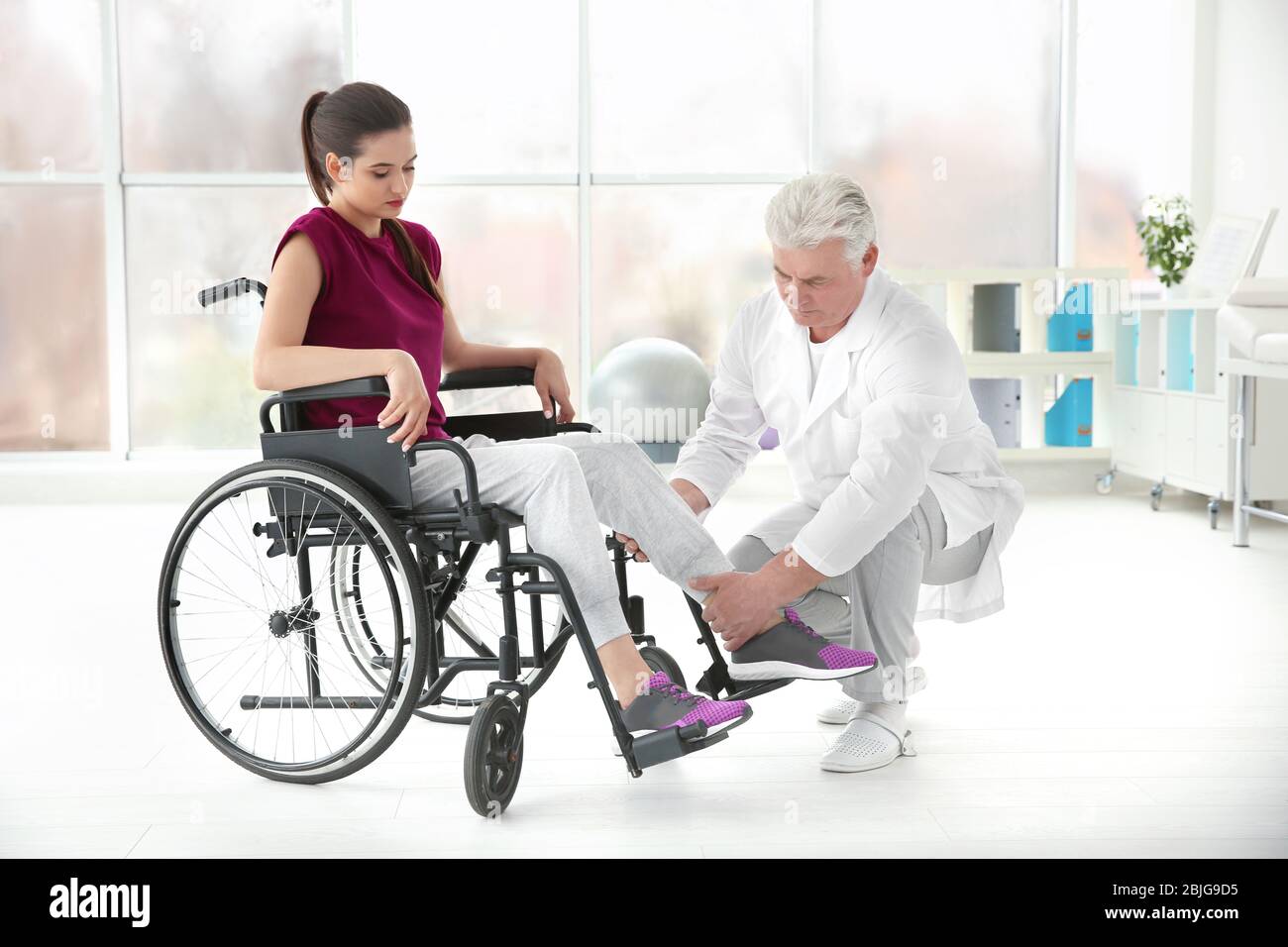 Young disabled woman with senior orthopedist in rehabilitation clinic ...