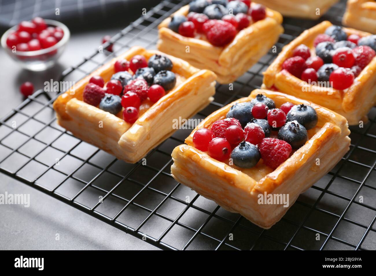 Delicious puff pastry dessert with berries on baking grid, closeup ...