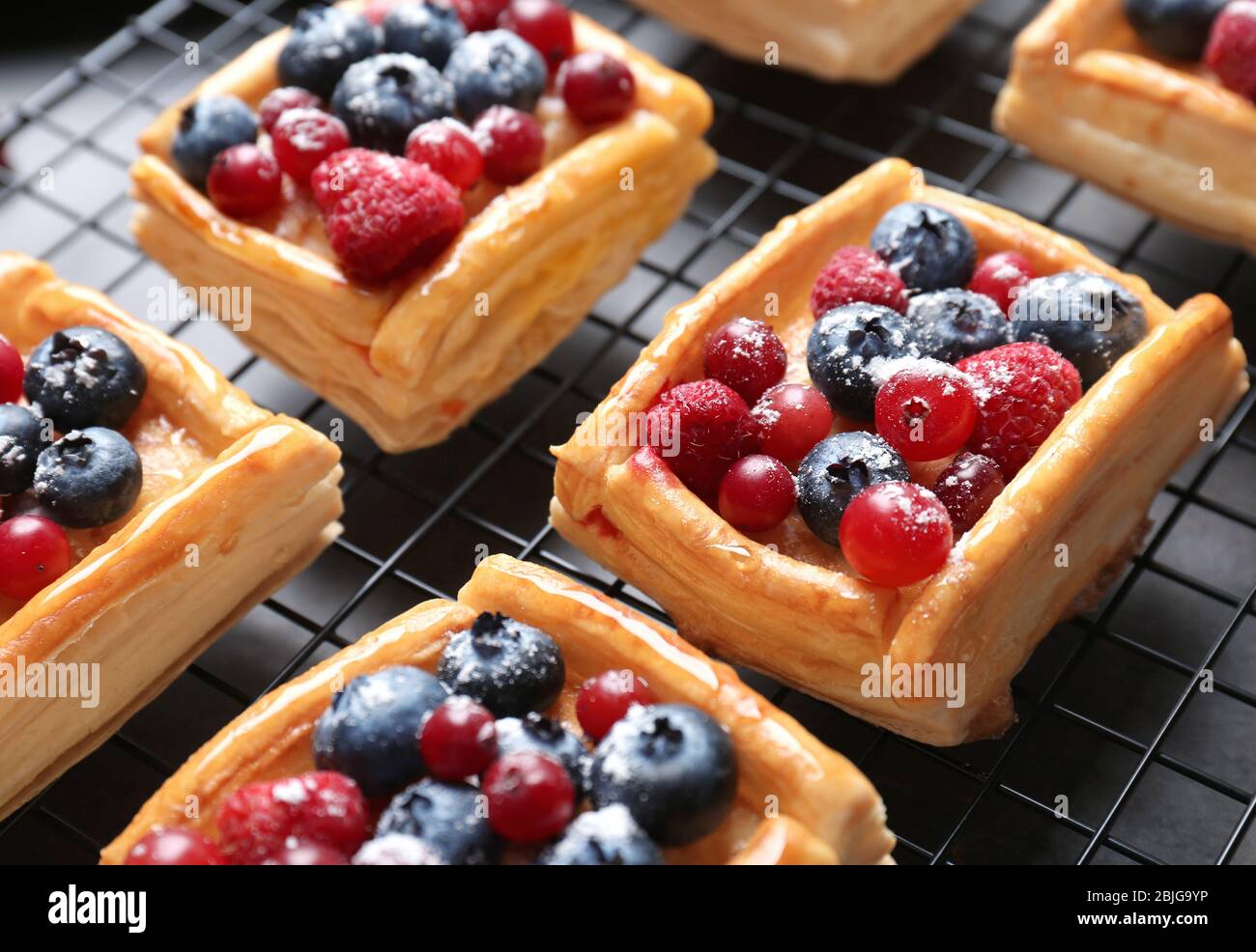 Delicious puff pastry dessert with berries on baking grid, closeup ...