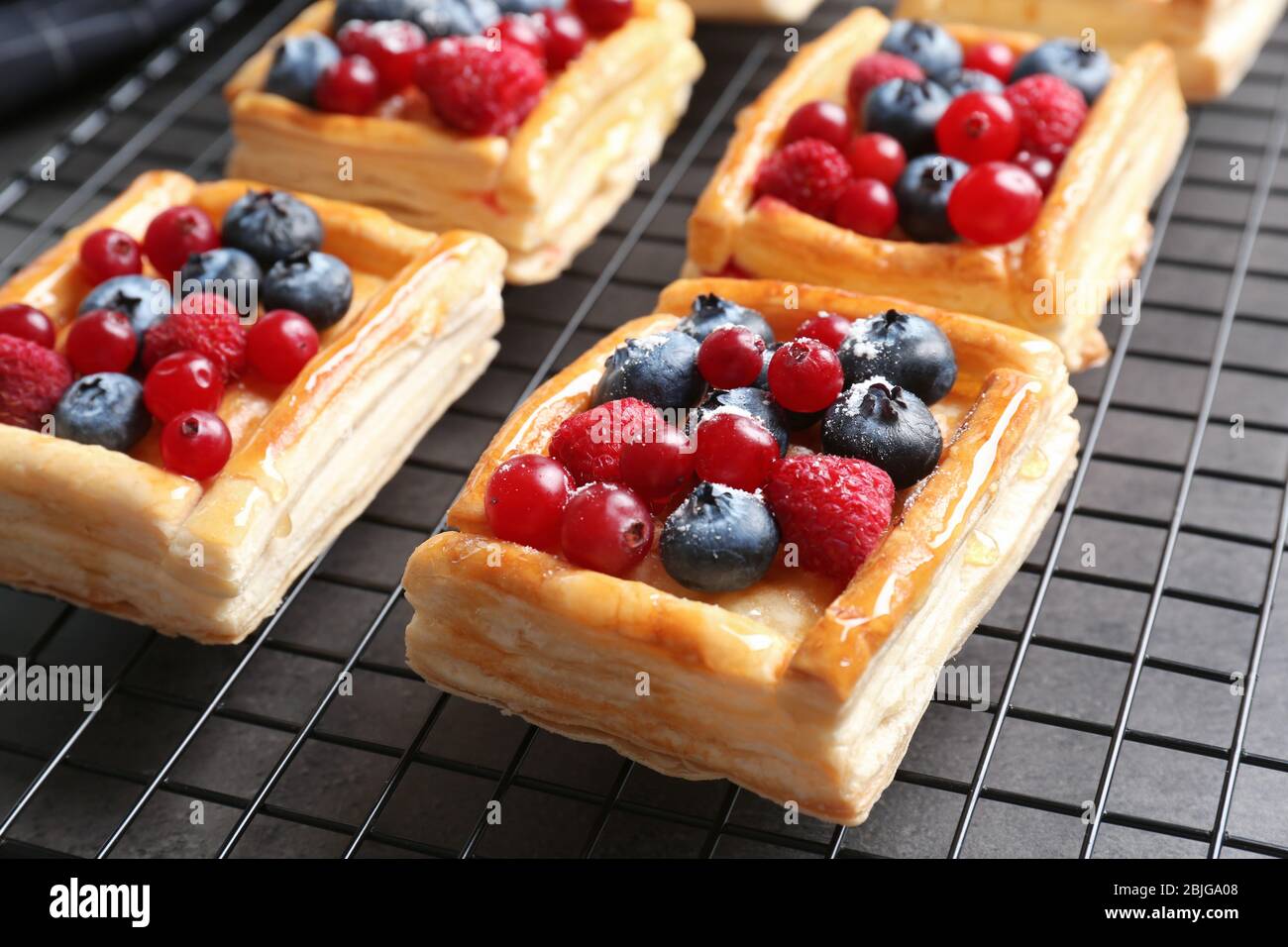 Delicious puff pastry dessert with berries on baking grid, closeup ...