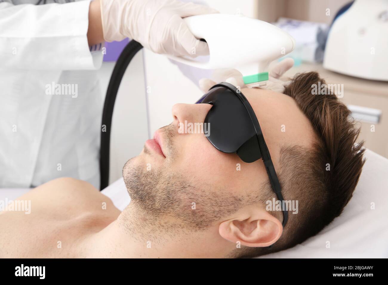 Handsome man getting laser epilation in beauty salon Stock Photo - Alamy