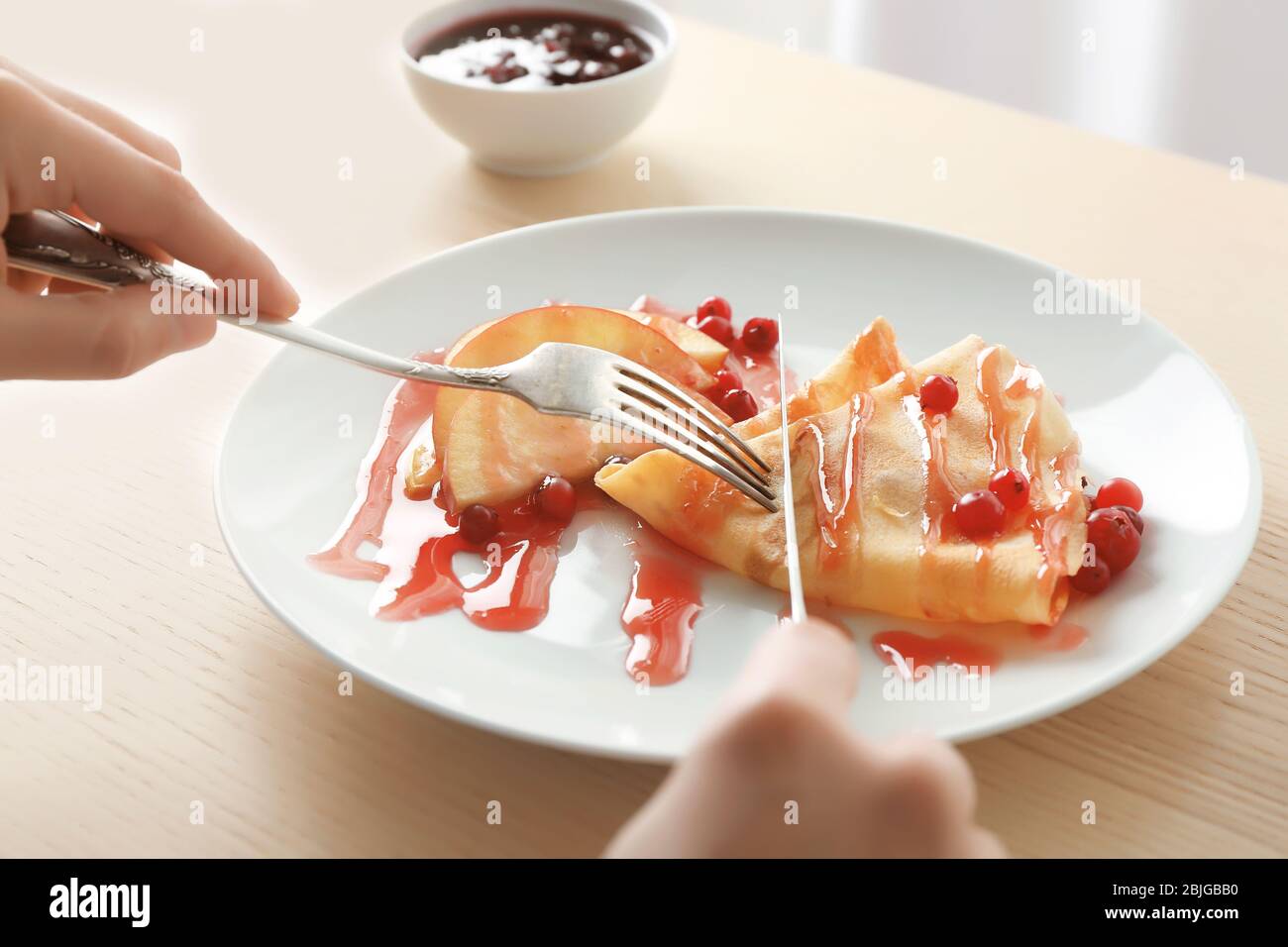 Person eating tasty crepe for breakfast on table Stock Photo - Alamy