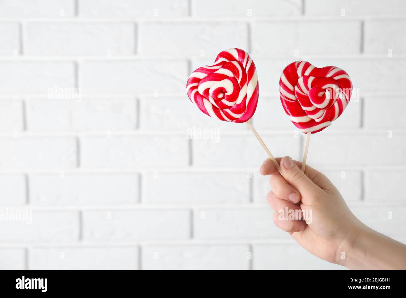 Female hand with tasty lollipops near brick wall Stock Photo - Alamy