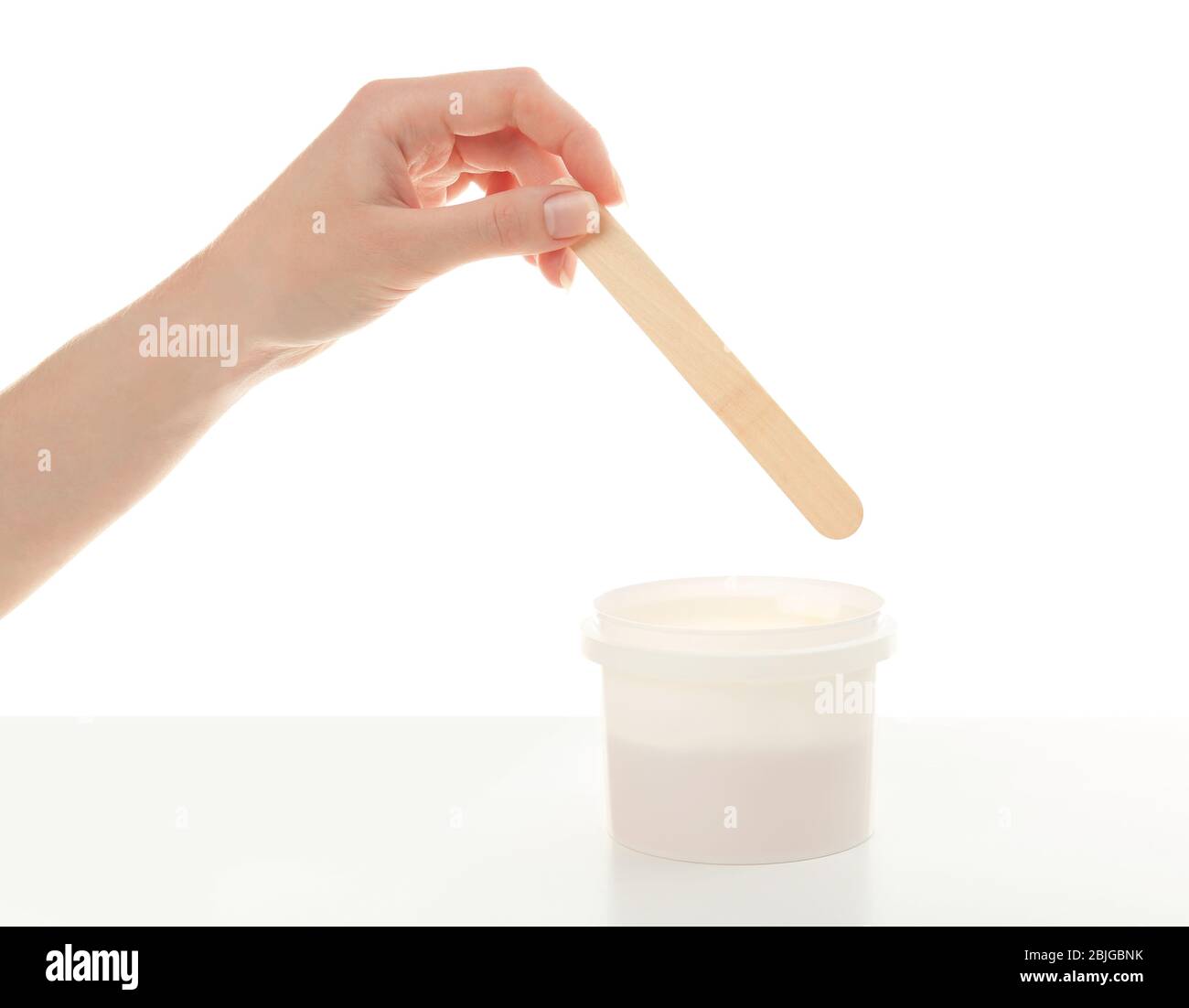 Female hand with wooden stick and sugaring paste on white background ...