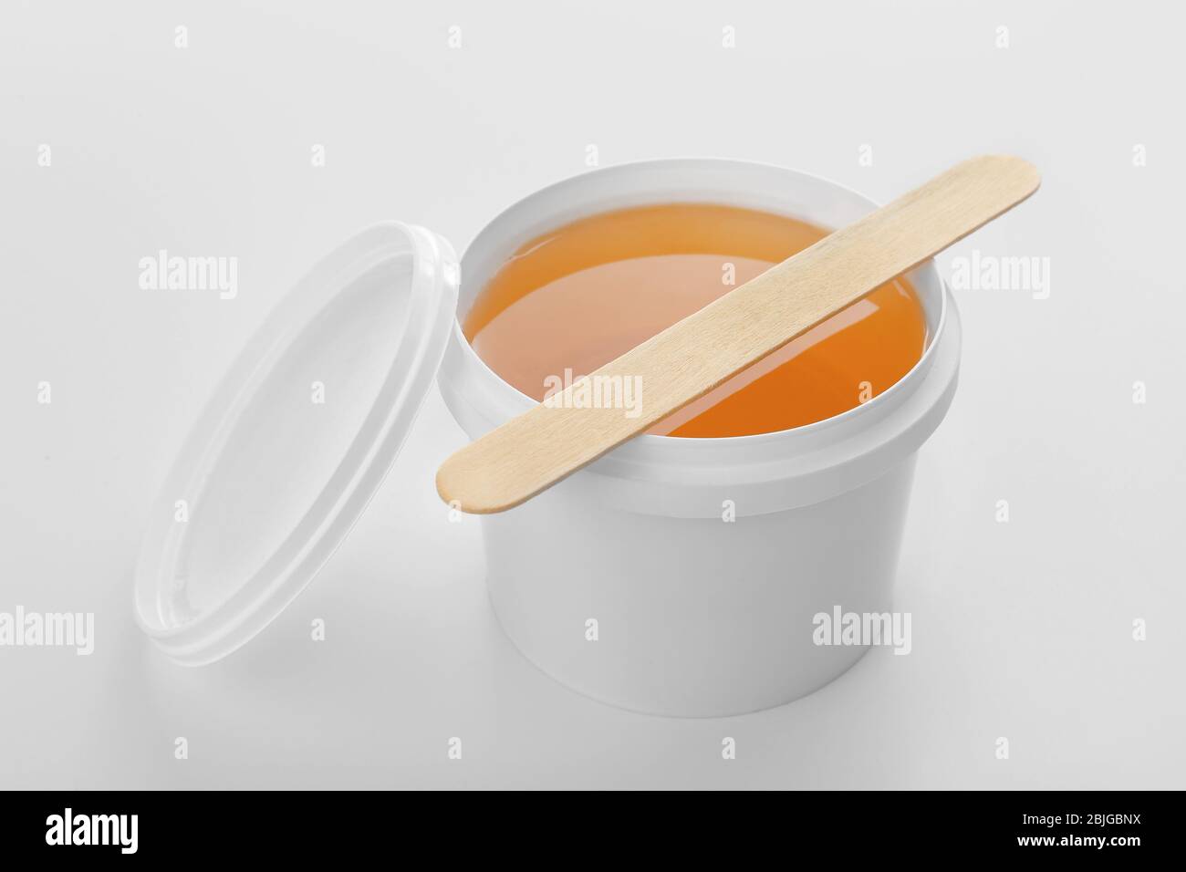 Plastic bucket with sugaring paste and stick on white background Stock ...