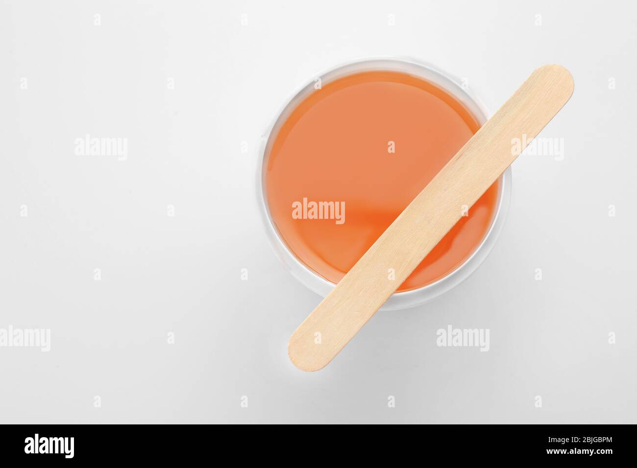 Plastic bucket with sugaring paste and stick on white background Stock ...